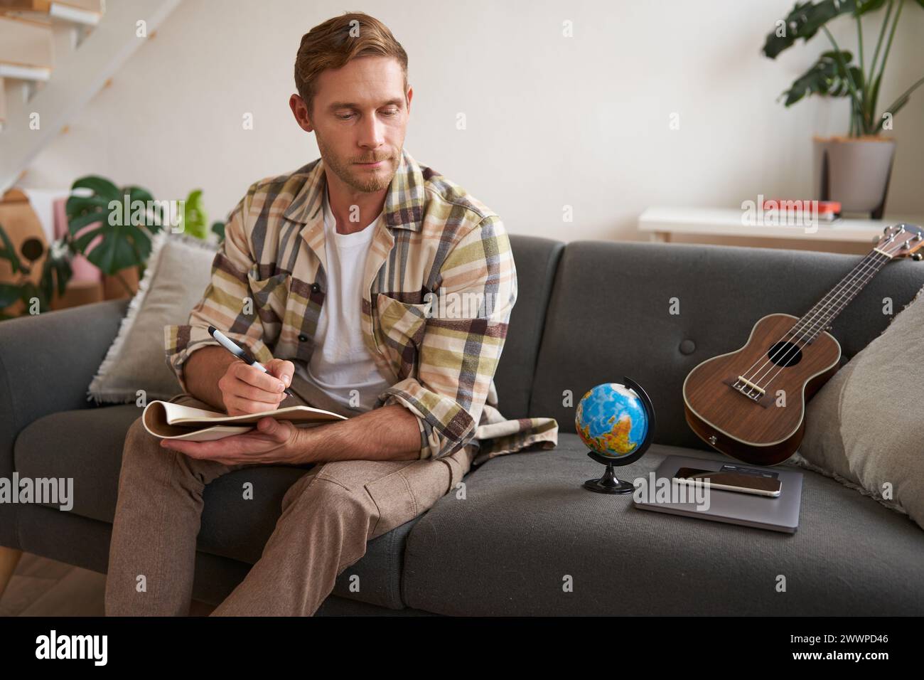 Man writing check-list, packing for holiday, cross-reference items with ...
