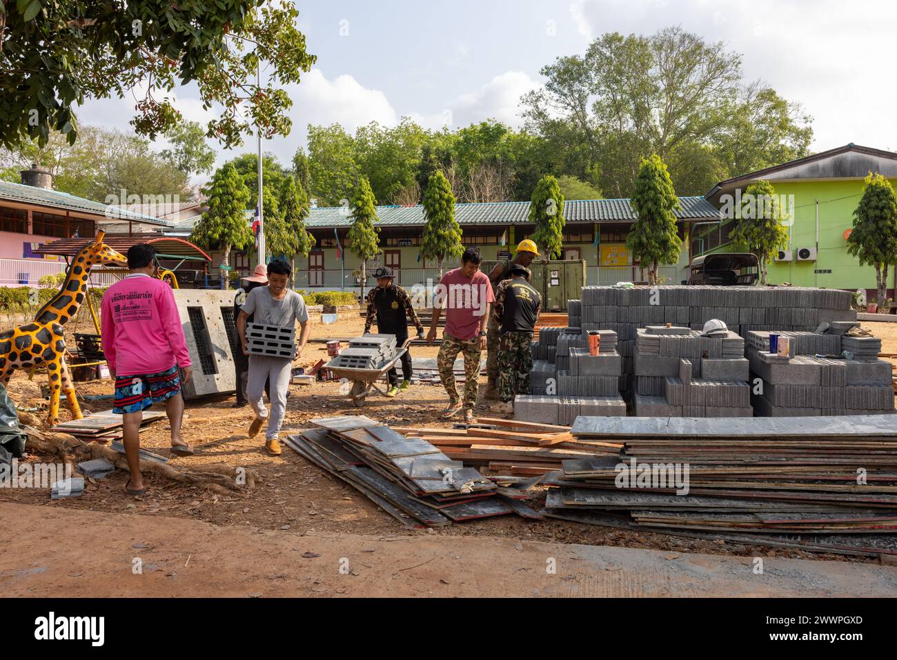 Members of the Ban Prakaet village carry bricks to the new school room ...