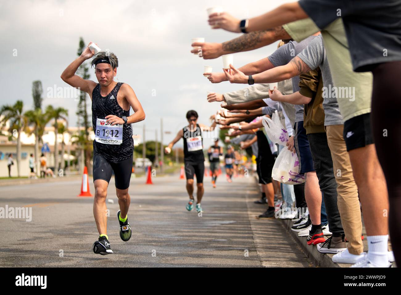 Runners take water from volunteers during the Okinawa Marathon at ...