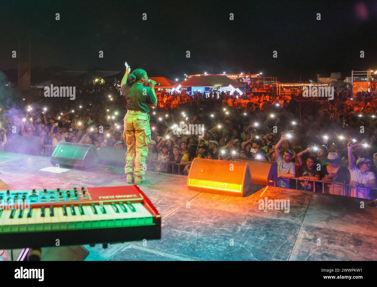 Audience members waive their cell phone lights as they sing along with ...