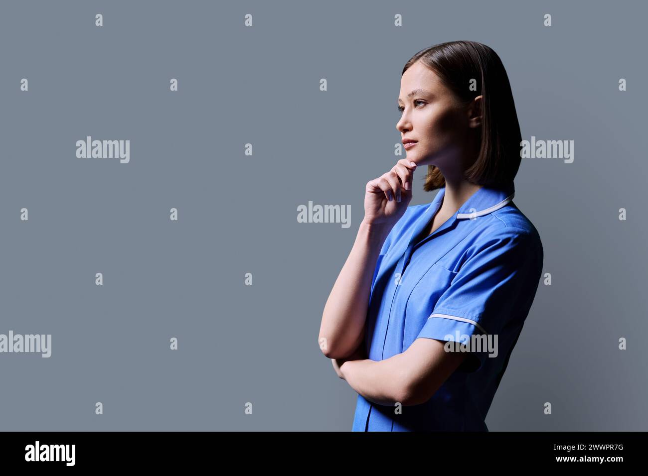 Portrait of young female nurse looking in profile on gray background ...
