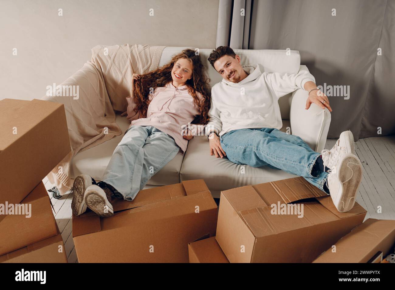 Happy young family couple man and woman relaxing on sofa after moving ...