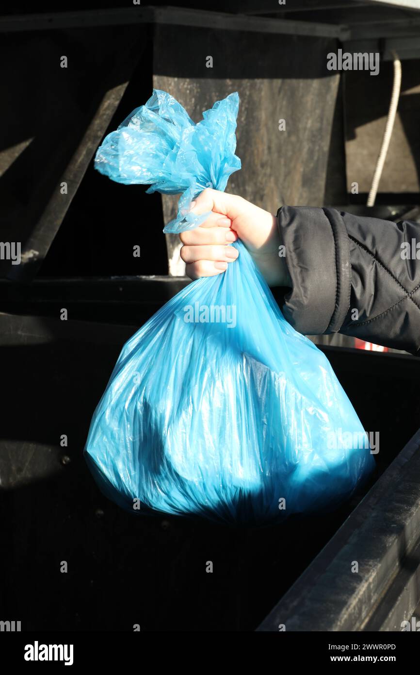 Woman throwing trash bag full of garbage in bin outdoors, closeup Stock ...