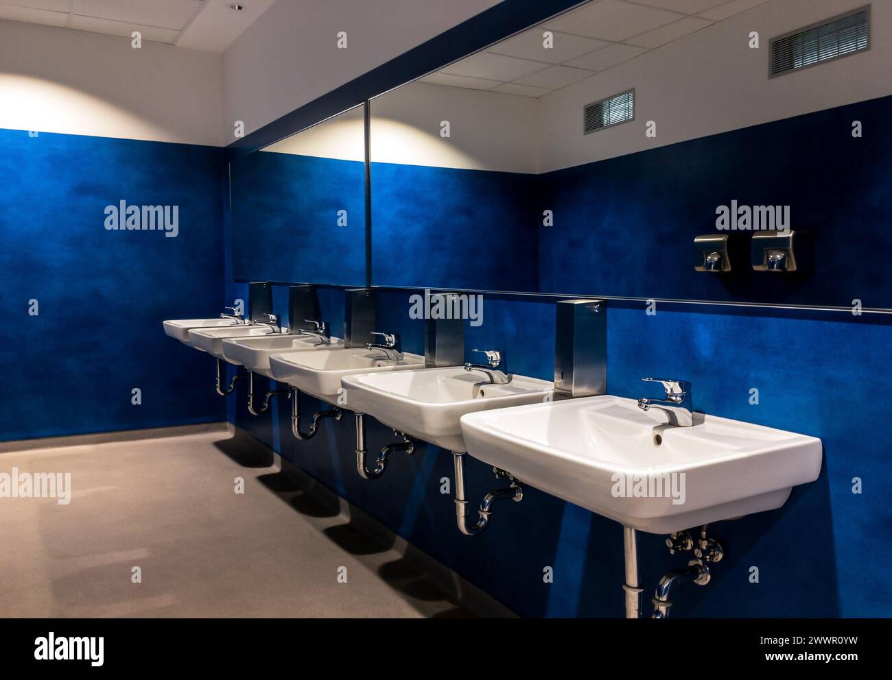 Six wash-basins in a modern blue restroom with large mirrors Stock ...