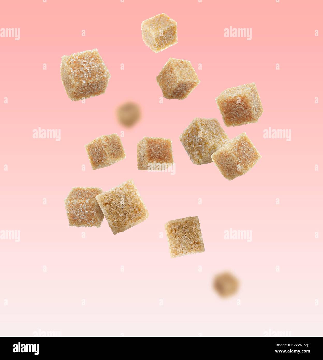 Brown cane sugar cubes falling on pink gradient background Stock Photo ...
