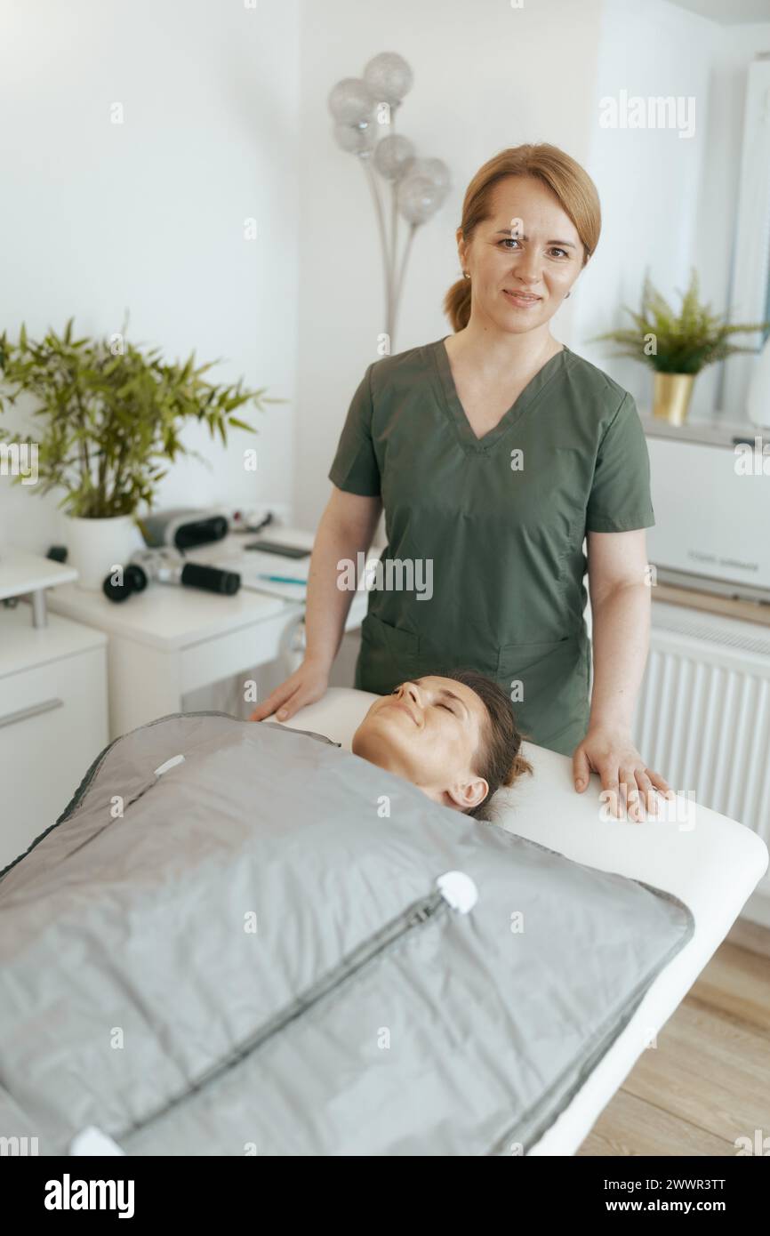Healthcare time. happy female medical massage therapist in massage cabinet with client doing ...
