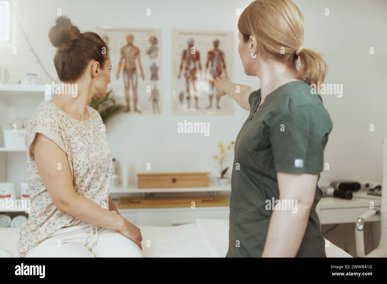 Healthcare time. Seen from behind female massage therapist in massage ...