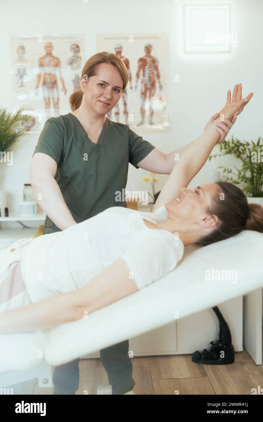 Healthcare time. happy female massage therapist in massage cabinet with client doing checkup ...