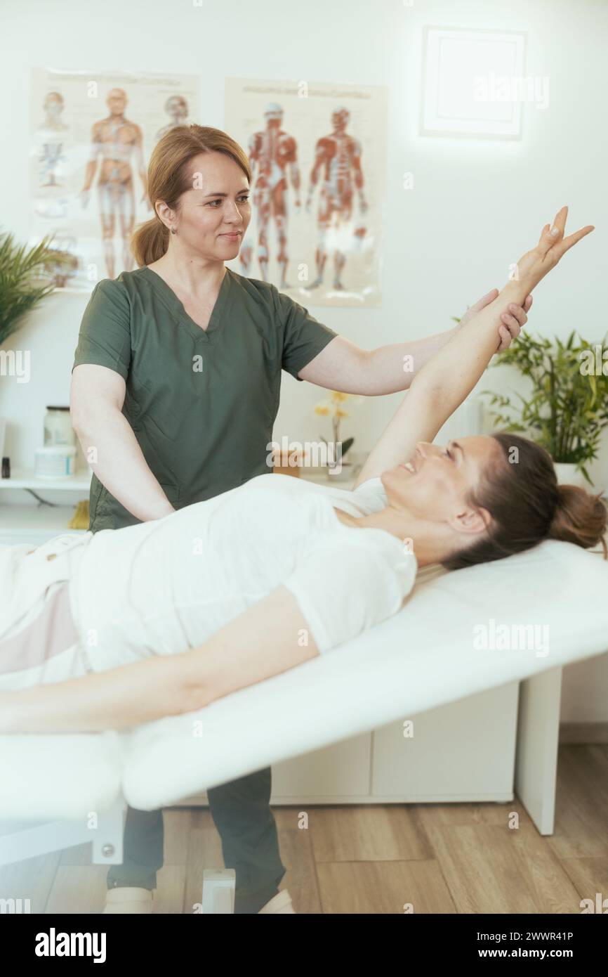 Healthcare time. smiling female medical massage therapist in massage cabinet with client ...