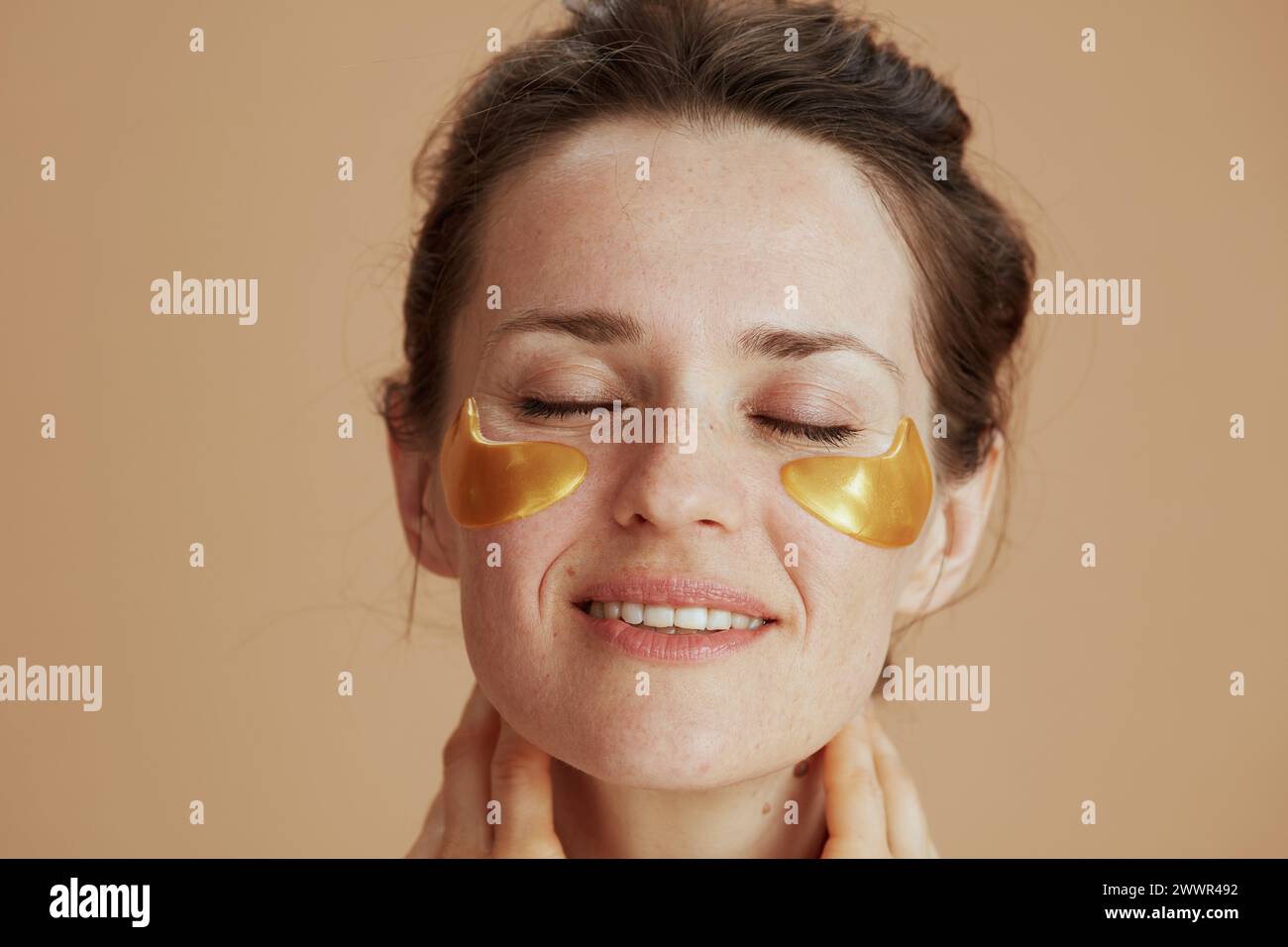 smiling modern woman with eye patches on beige background Stock Photo ...