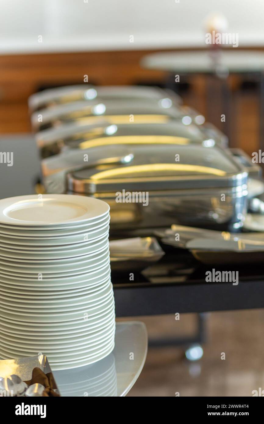 Stack of plates next to closed chafing dishes at party banquet hall ...