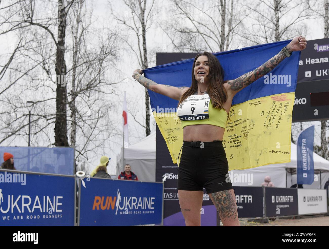 Non Exclusive: KYIV, UKRAINE - MARCH 24, 2024 - A runner holds a signed Ukrainian flag during ...