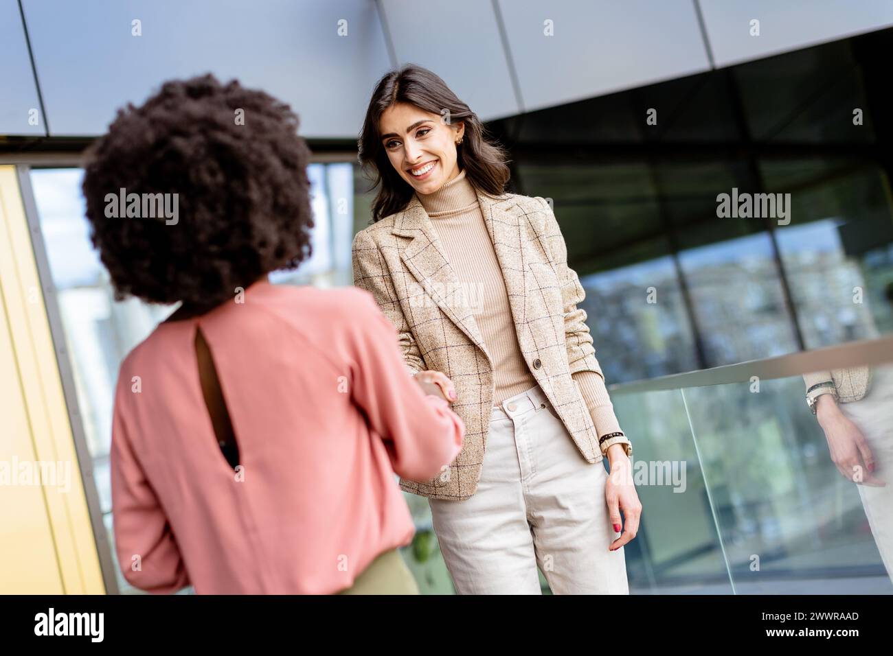 Two women engage in a friendly handshake, one laughing joyously ...