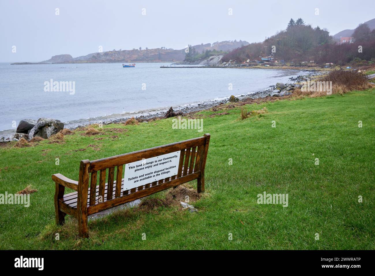 An abandoned wooden seat with no people. A drizzly day at Carsaig Beach ...