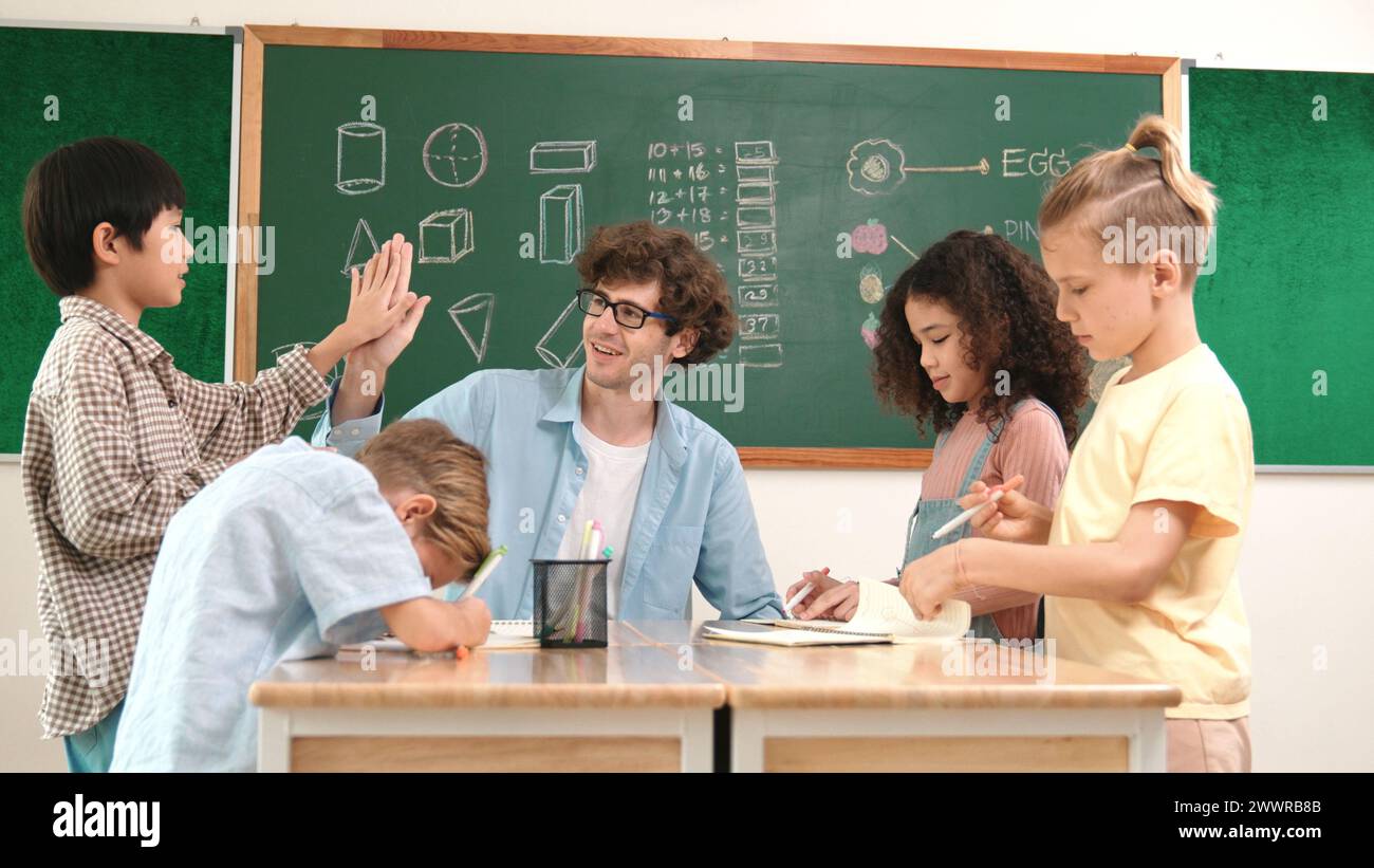 Caucasian teacher giving high five to encourage children to working ...