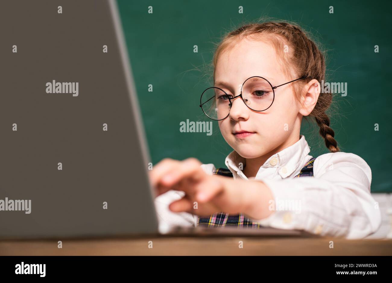 Pupil girl working on a laptop. Cute little preschool kid boy study in ...
