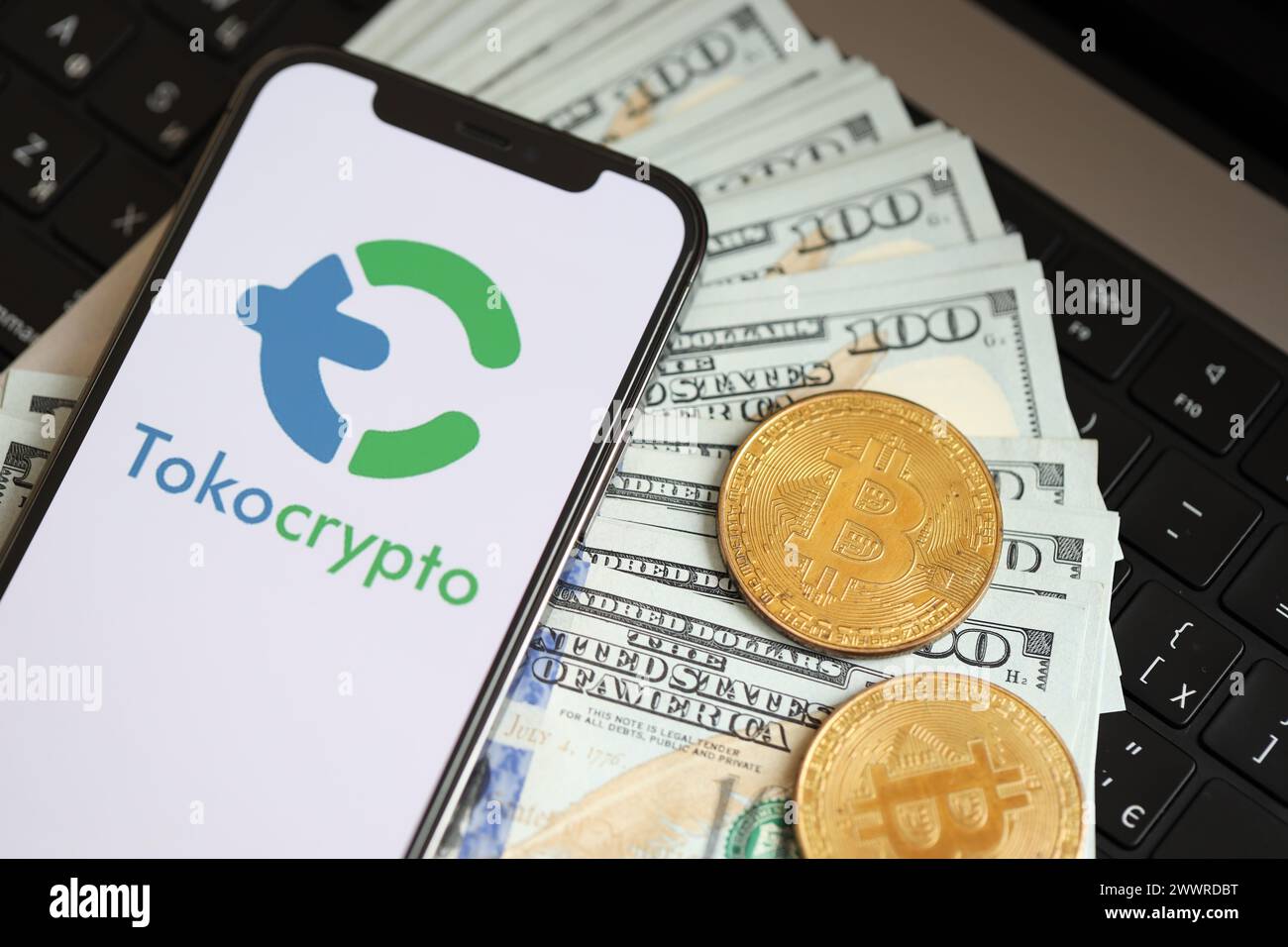 KYIV, UKRAINE - MARCH 15, 2024 Tokocrypto logo on iPhone display screen with dollars and ...