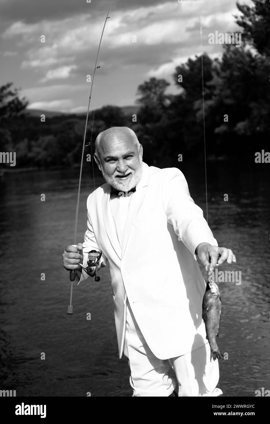 Fisherman caught a trout fish. Portrait of cheerful senior man fishing ...