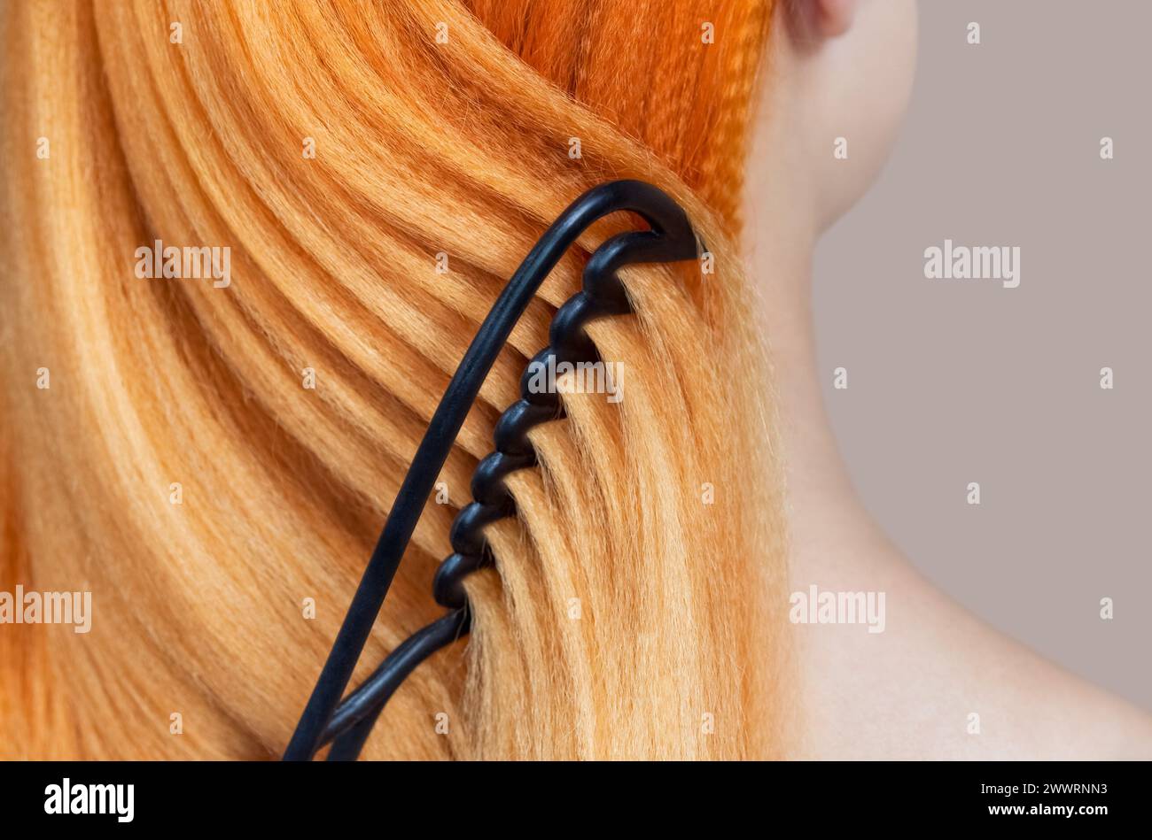 Hairdresser combing her long red hair of his client in the beauty salon ...
