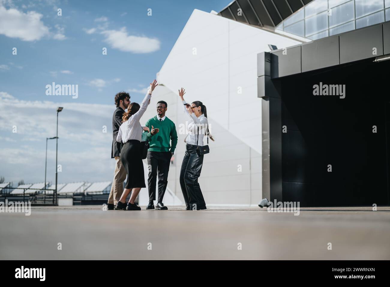 Enthusiastic business team celebrating success outdoors with high-five ...
