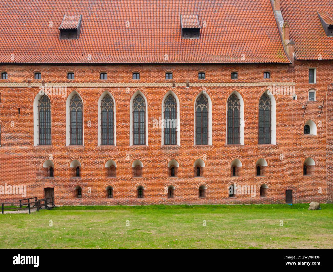 Brick wall with high gothic windows of castle chapel in Malbork, Poland ...