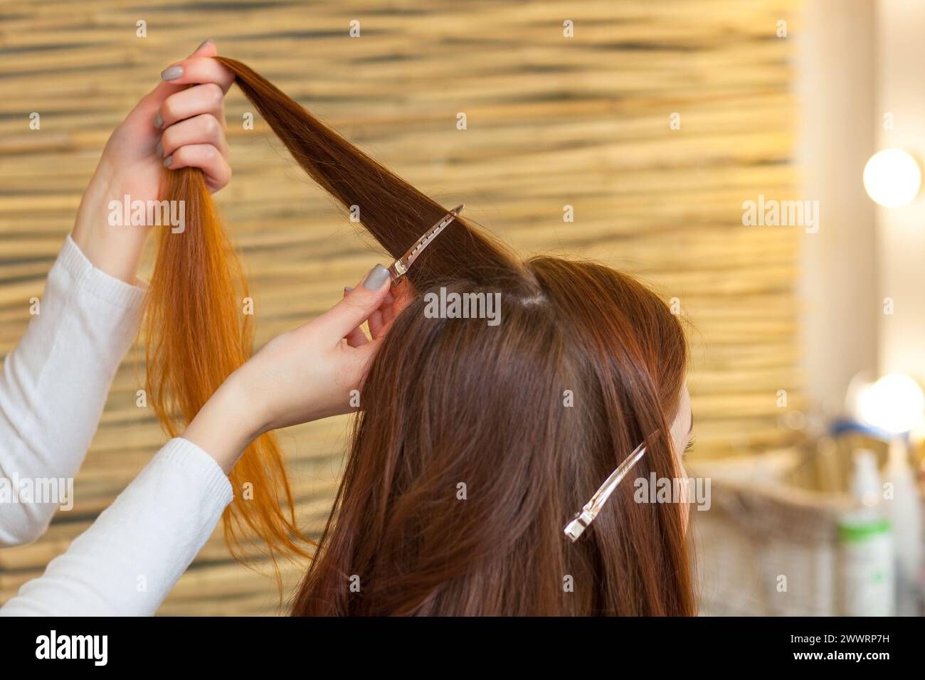 Hairdresser combing her long, red hair of his client in the beauty ...