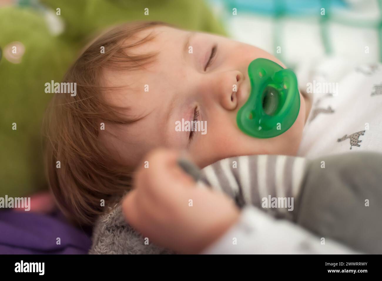 Cute baby boy sleeps peacefully with a pacifier, holding his favorite ...
