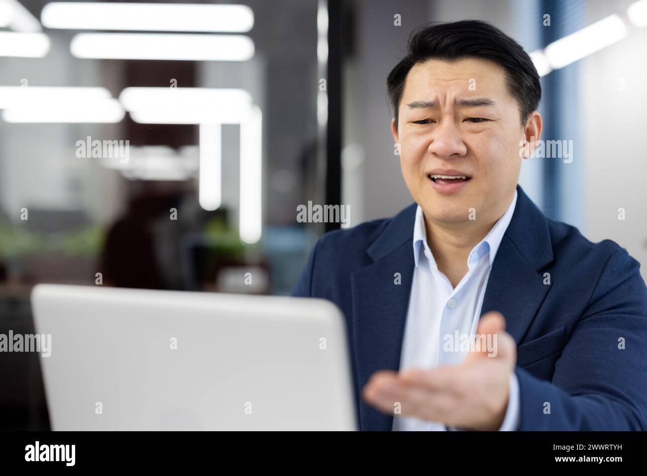 Shocked japanese male looking at screen of wireless laptop and feeling ...