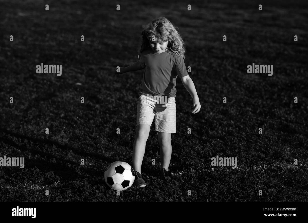 Soccer child play football. Kid kicking a football ball on a grass ...