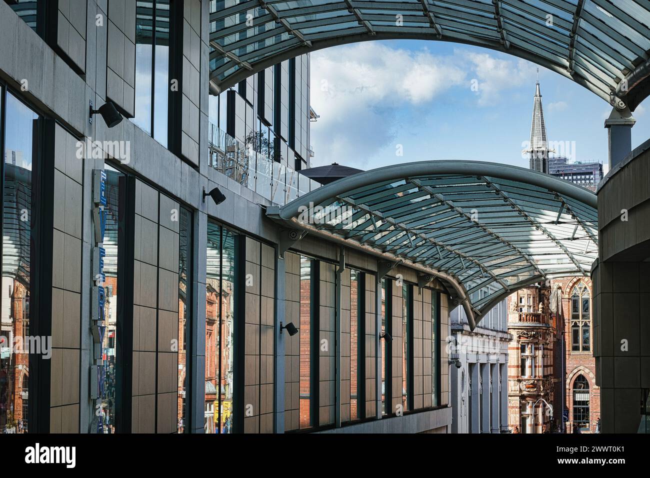 Modern glass-covered walkway with urban architecture and blue sky in ...
