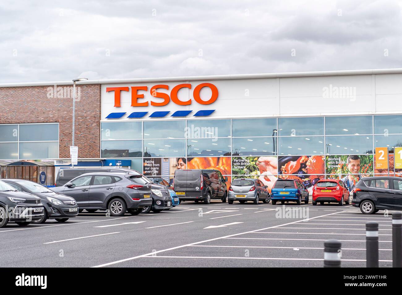 Exterior view of a UK Tesco superstore (supermarket) with parked cars ...