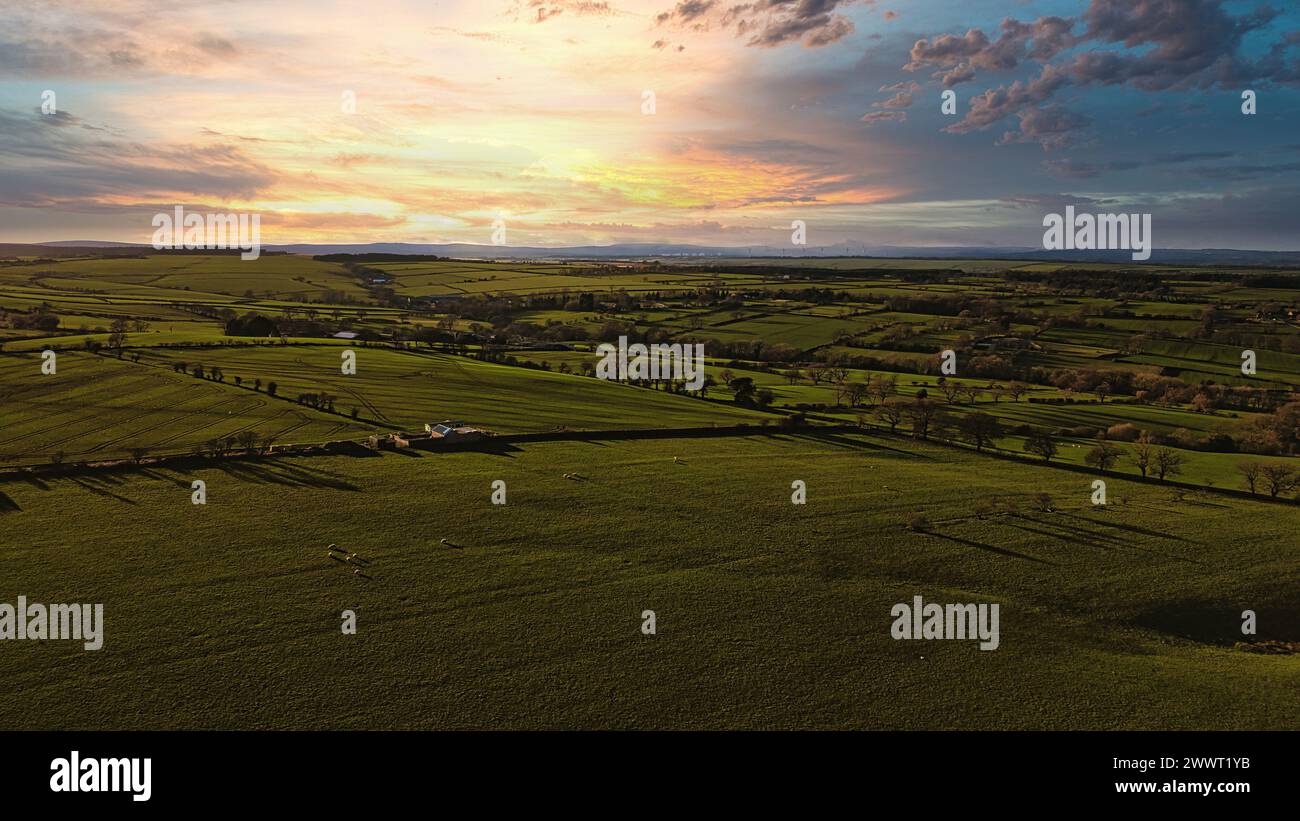 Aerial view of a lush green countryside under a dramatic sunset sky in ...