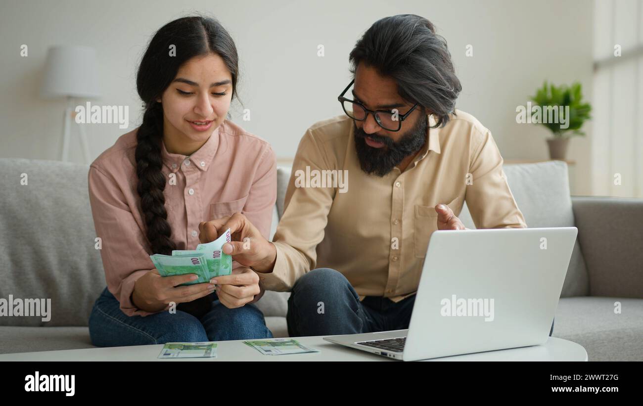 Arabian man Indian woman multiracial couple at home counting euro ...