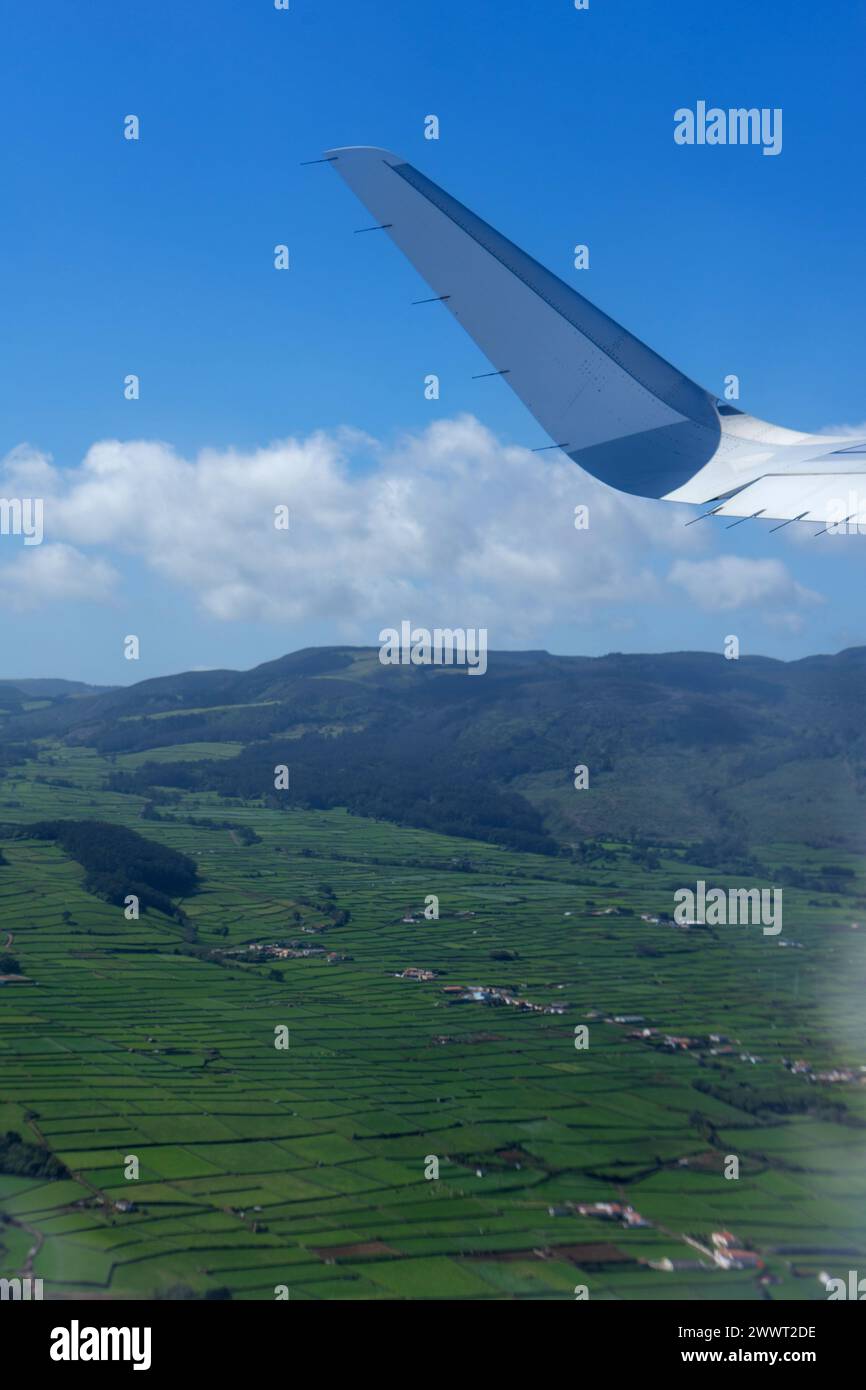 Wing of airplane soaring over fields on Terceira Island, Azores. Aerial ...