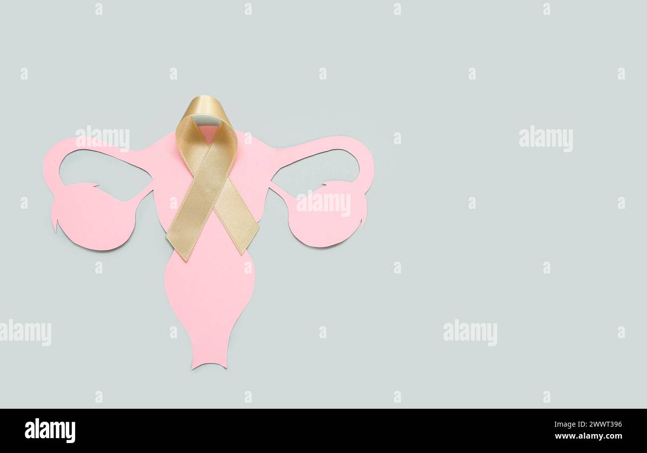 Paper uterus with beige ribbon on light background. Cancer awareness ...