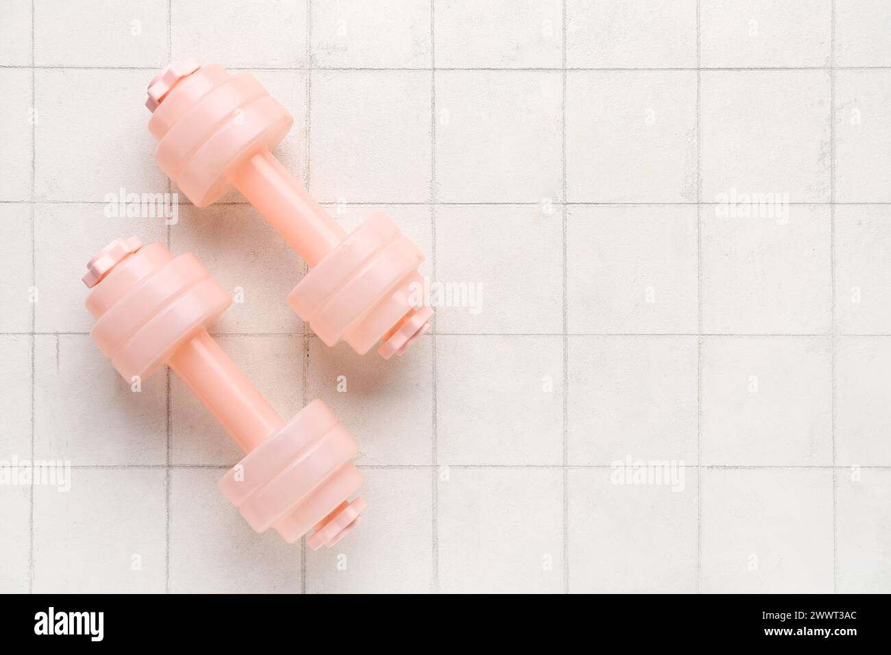 Pink dumbbells on white tile background Stock Photo - Alamy