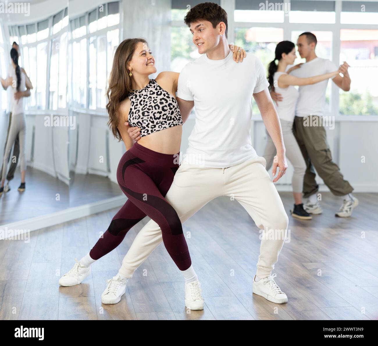 Smiling young woman in sports clothes learn to dance couples latin ...