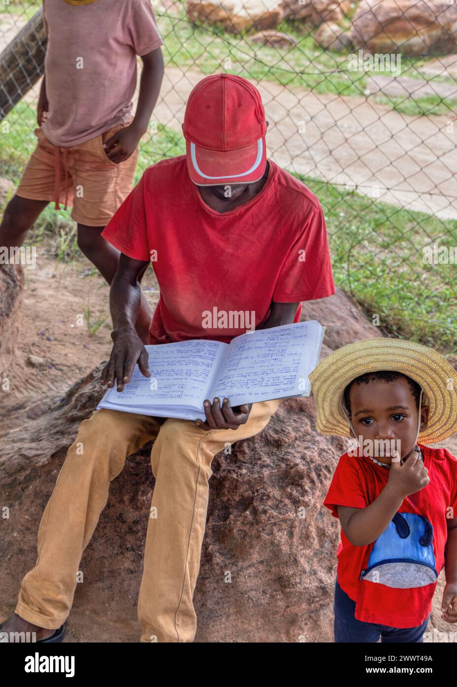 african social worker , reading from a book to the village children ...
