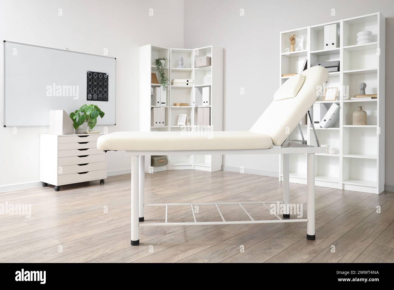 Interior of neurologist's office with medical couch and shelf units ...