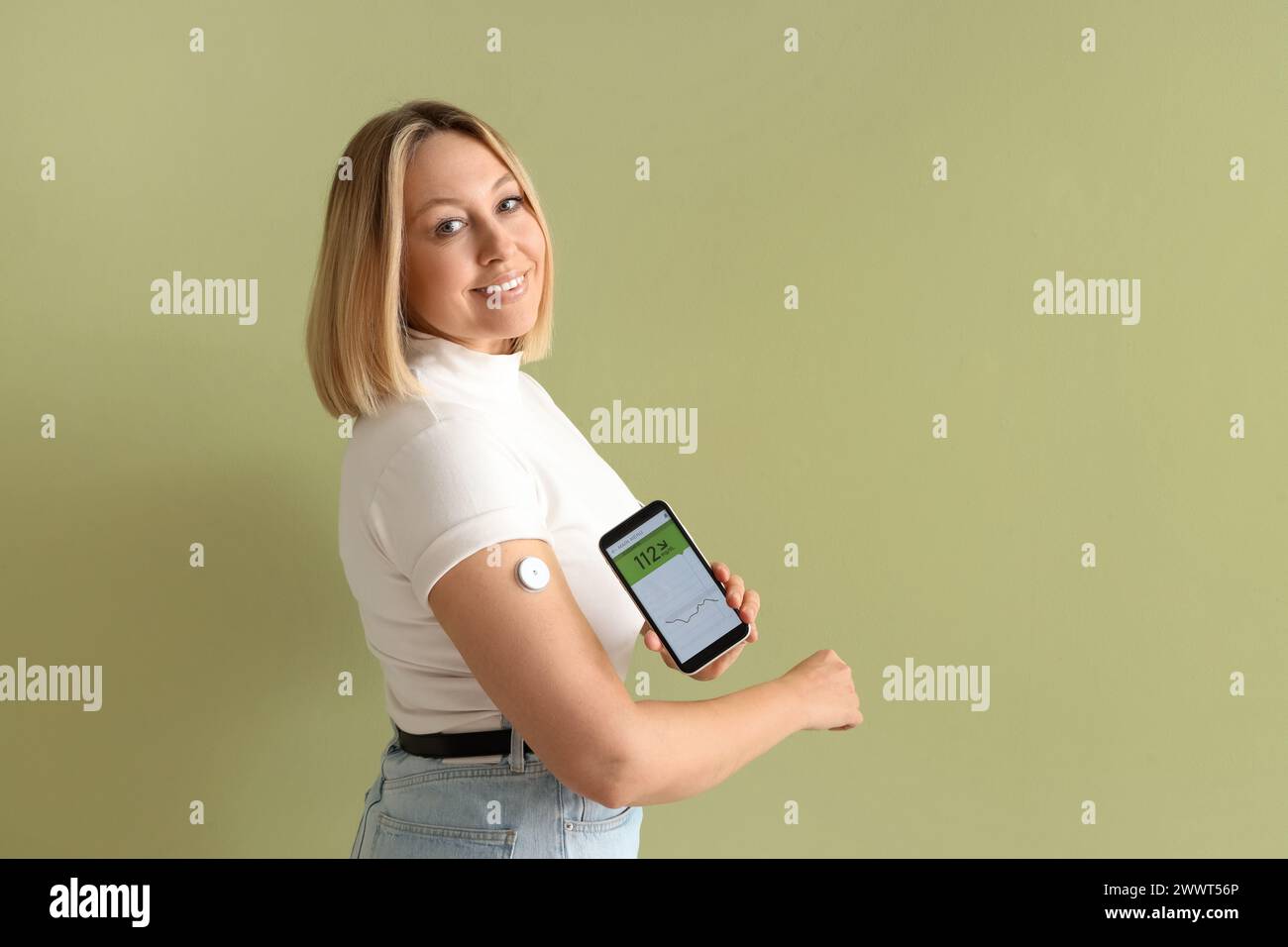 Diabetic woman with glucose sensor using mobile phone for measuring ...
