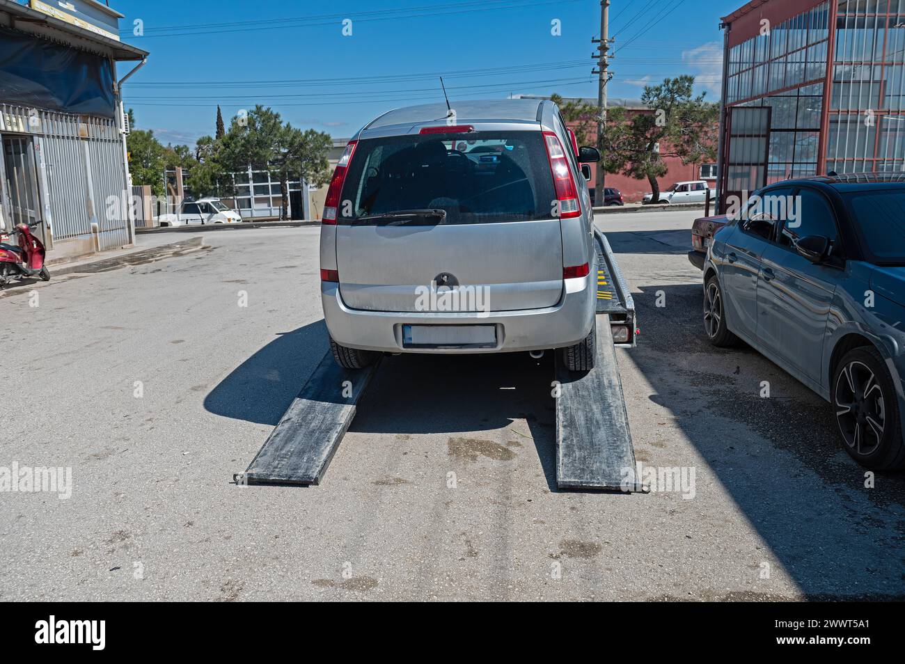 A man loading a broken down car onto a tow truck. Roadside assistance ...