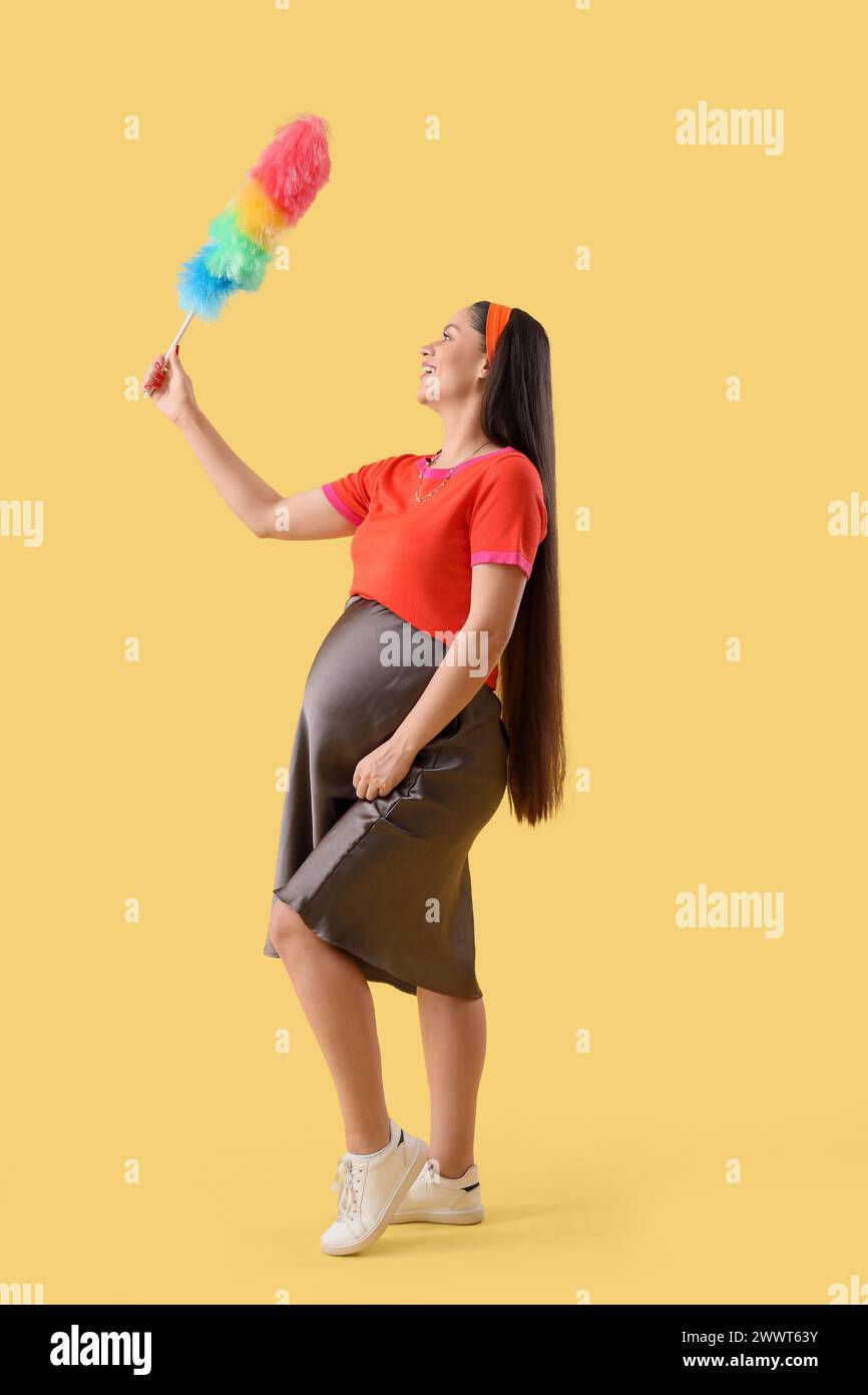 Young pregnant woman with pp-duster on yellow background Stock Photo ...