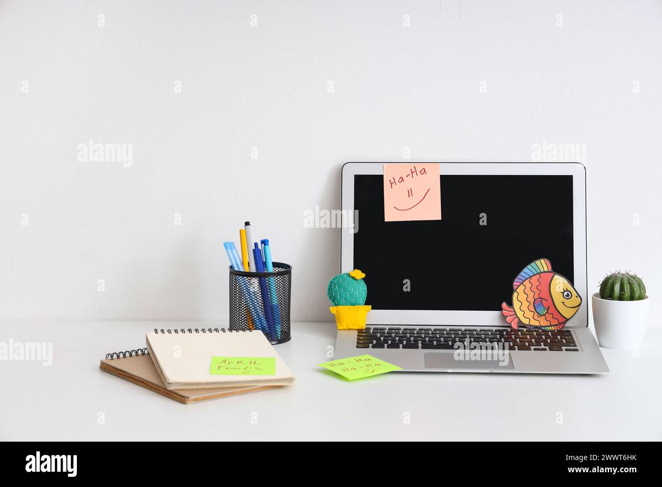 Workspace with laptop, funny sticky notes and paper fish on white ...