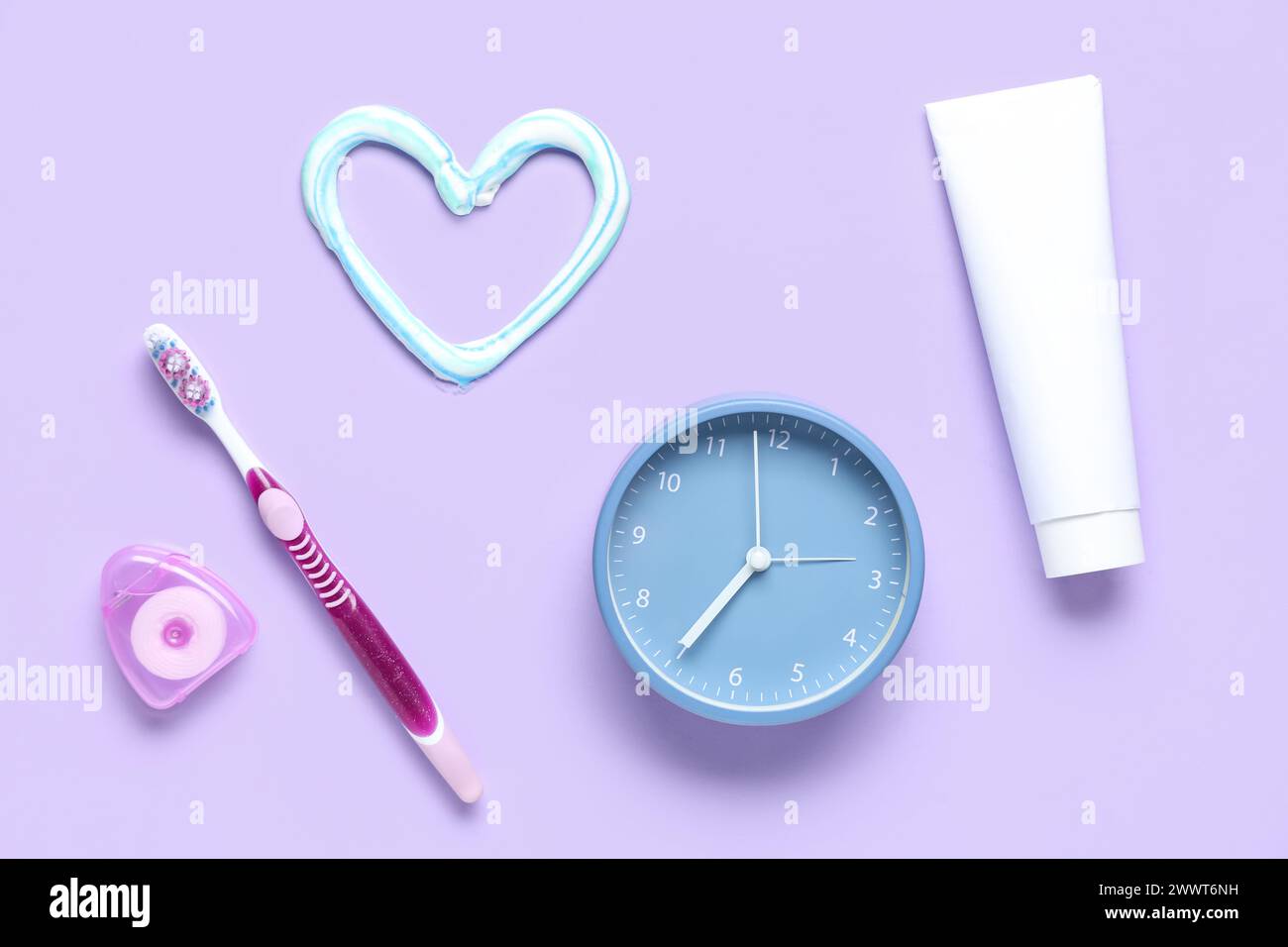 Heart made of toothpaste, clock, dental floss and toothbrush on lilac ...
