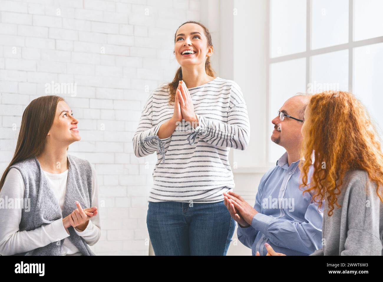 Community members clapping to woman, supporting her at therapy group ...
