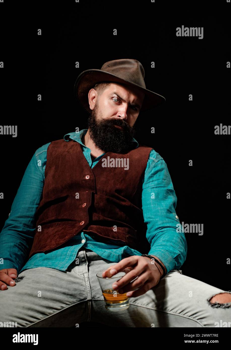 Man with beard holds glass of brandy. An elegant man suffering from ...