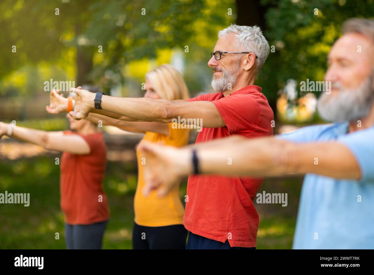 Senior adults participate in stretching exercise, extending their arms ...