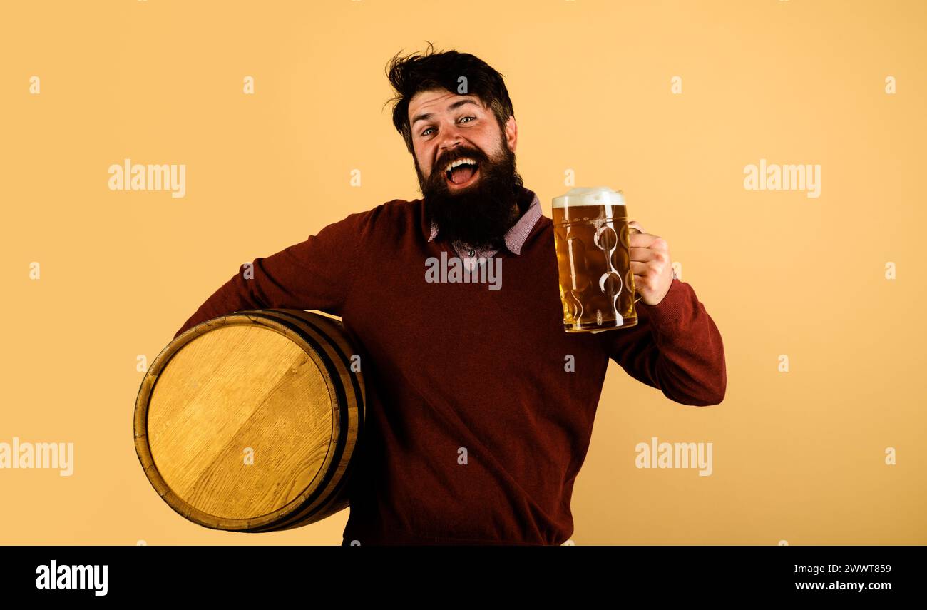 Beer time. Happy brewer with wooden barrel and mug of beer. Bearded man ...