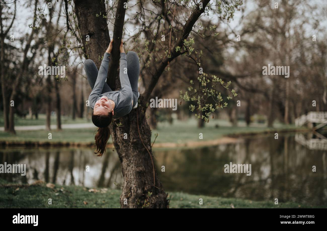 Active sporty girl enjoying nature, hanging upside down from a tree in ...