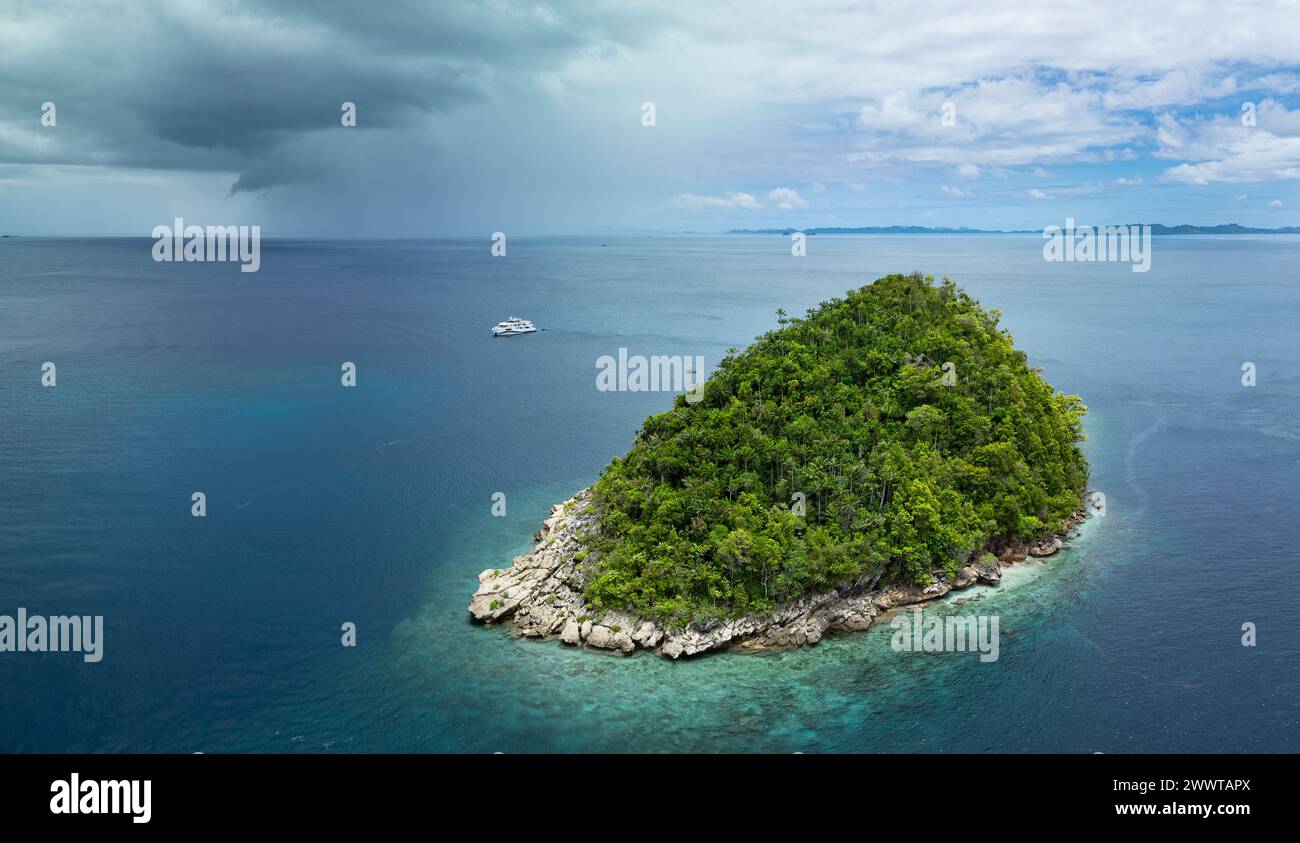 A limestone island, fringed by reef, rises from Raja Ampat's tropical ...